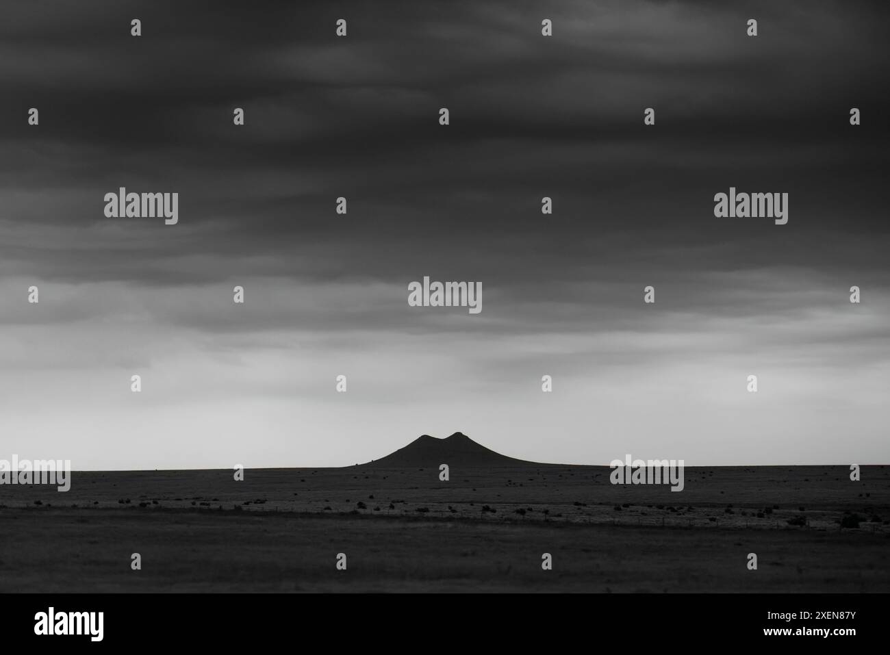 Black and white image of an old cinder cone volcano under moody skies ...