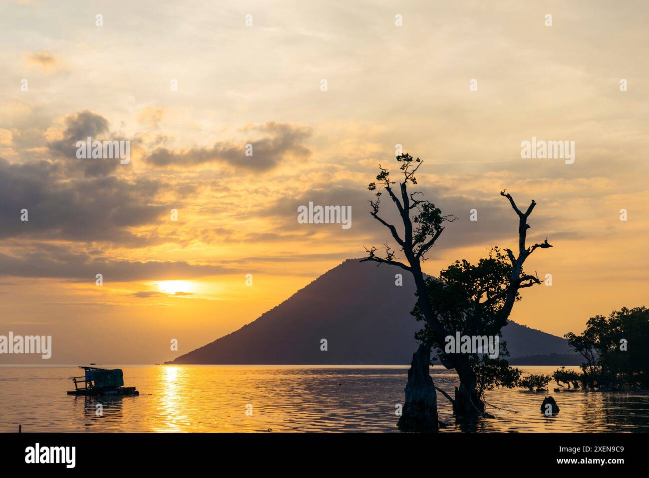 Sunset shines golden light over silhouetted island and tranquil ocean ...