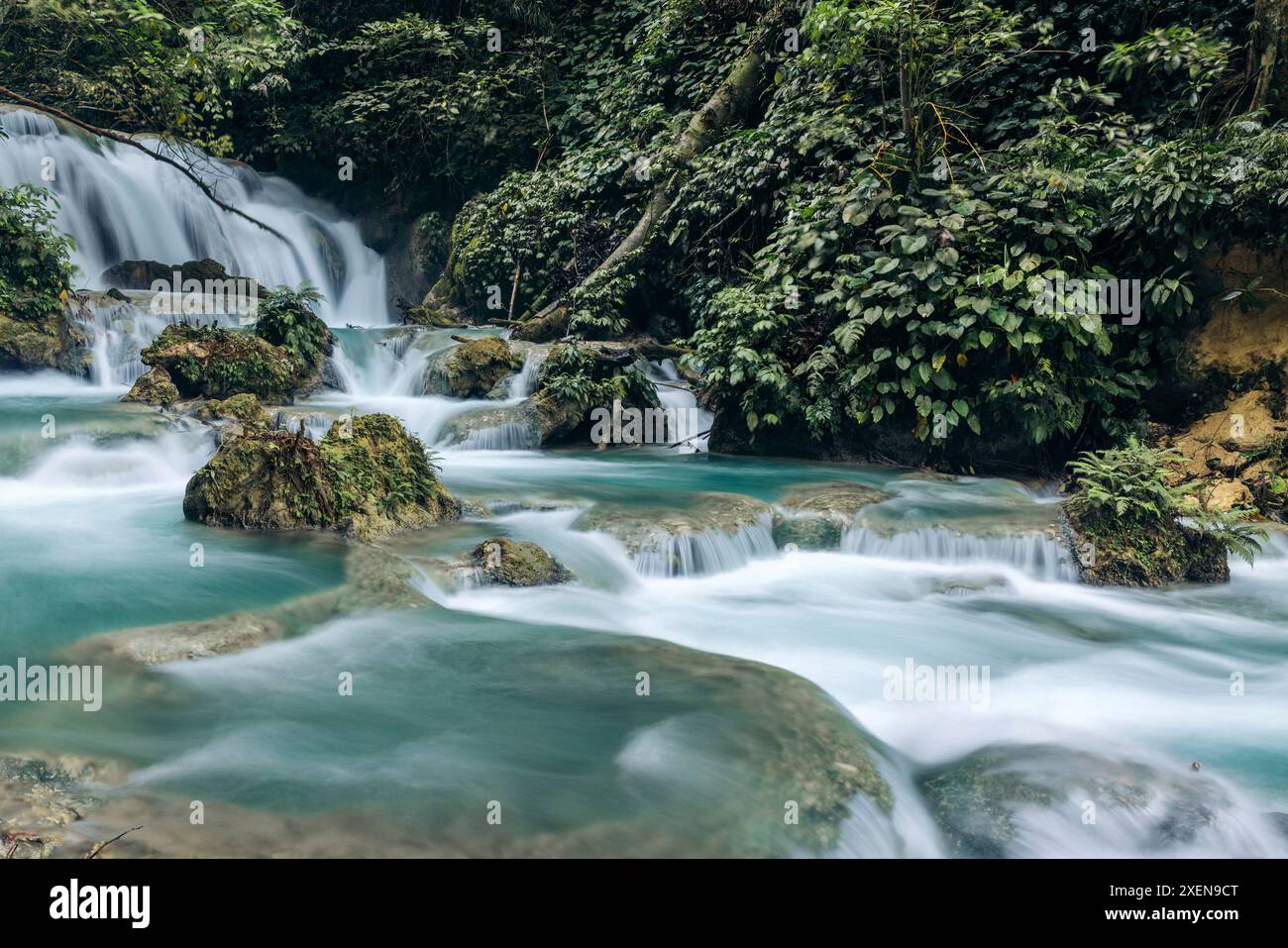 Long exposure of Piala waterfall cascading over rock with lush foliage ...