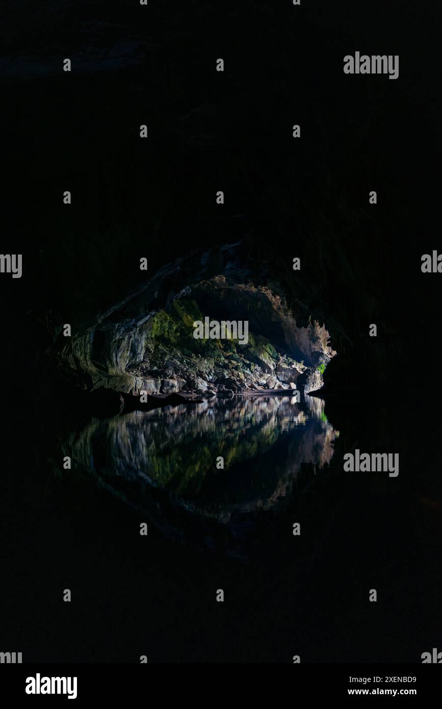 Rocky landscape with vegetation reflected in mirror image on a black ...