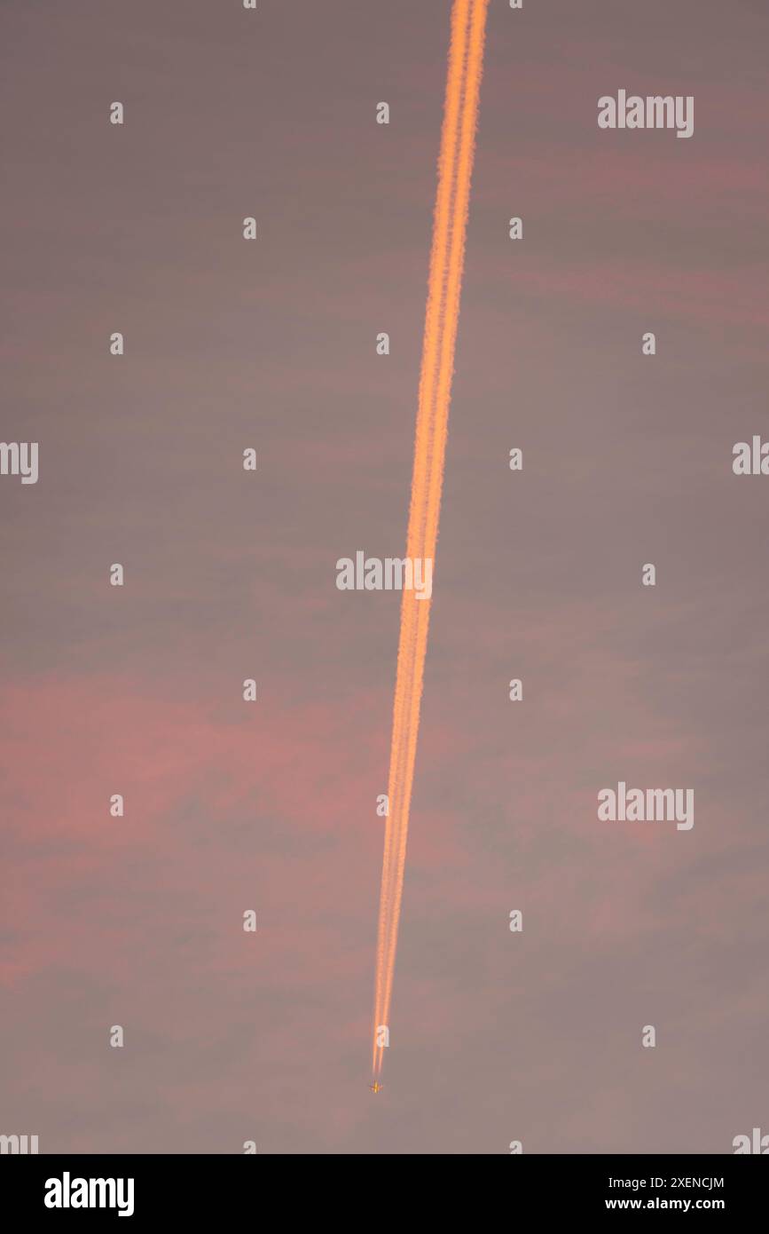 Airplane contrails in the sky backlit by sunset light; Makassar, South ...