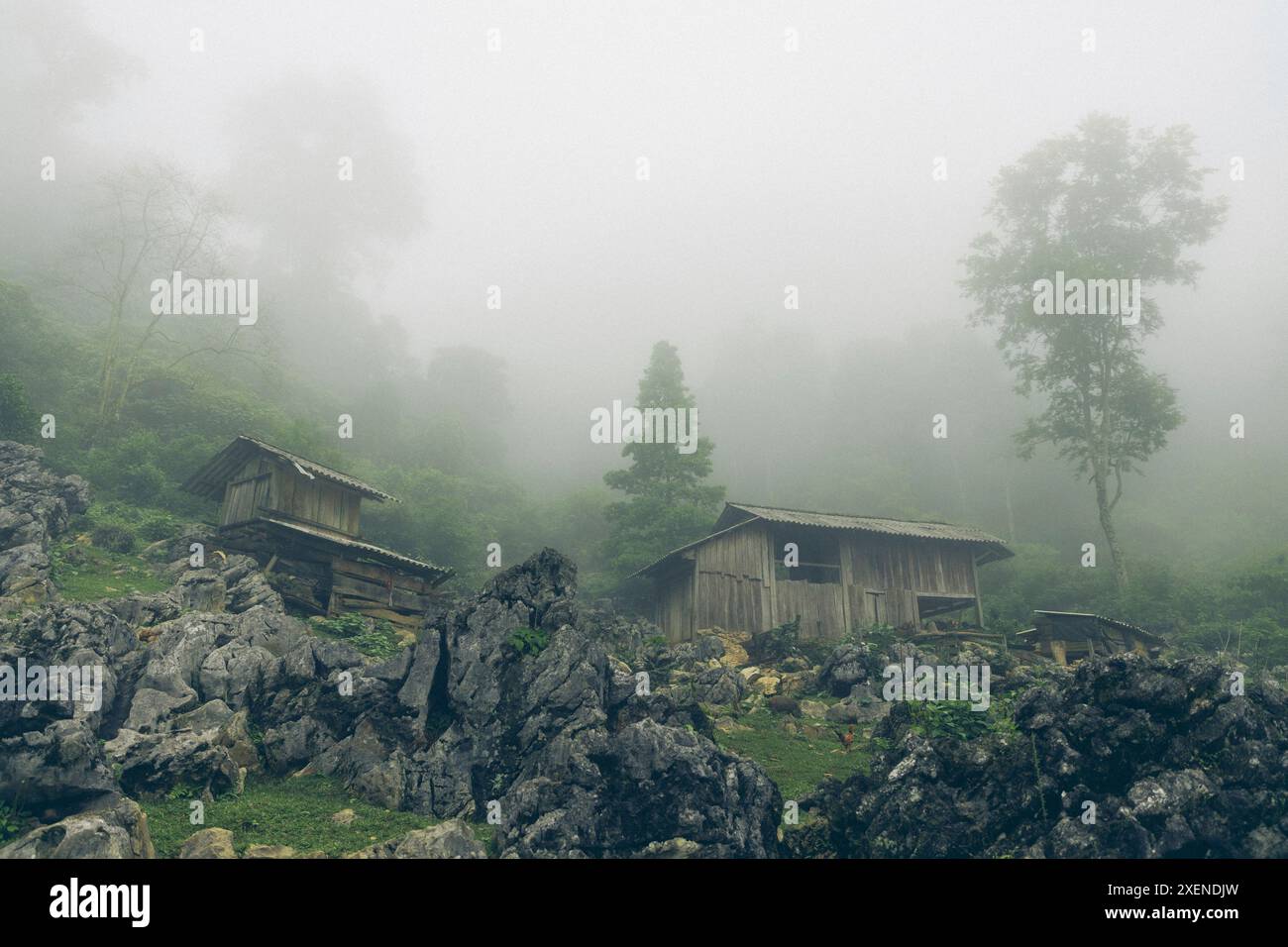 Traditional wooden structures built on a rocky terrain in the fog in a ...