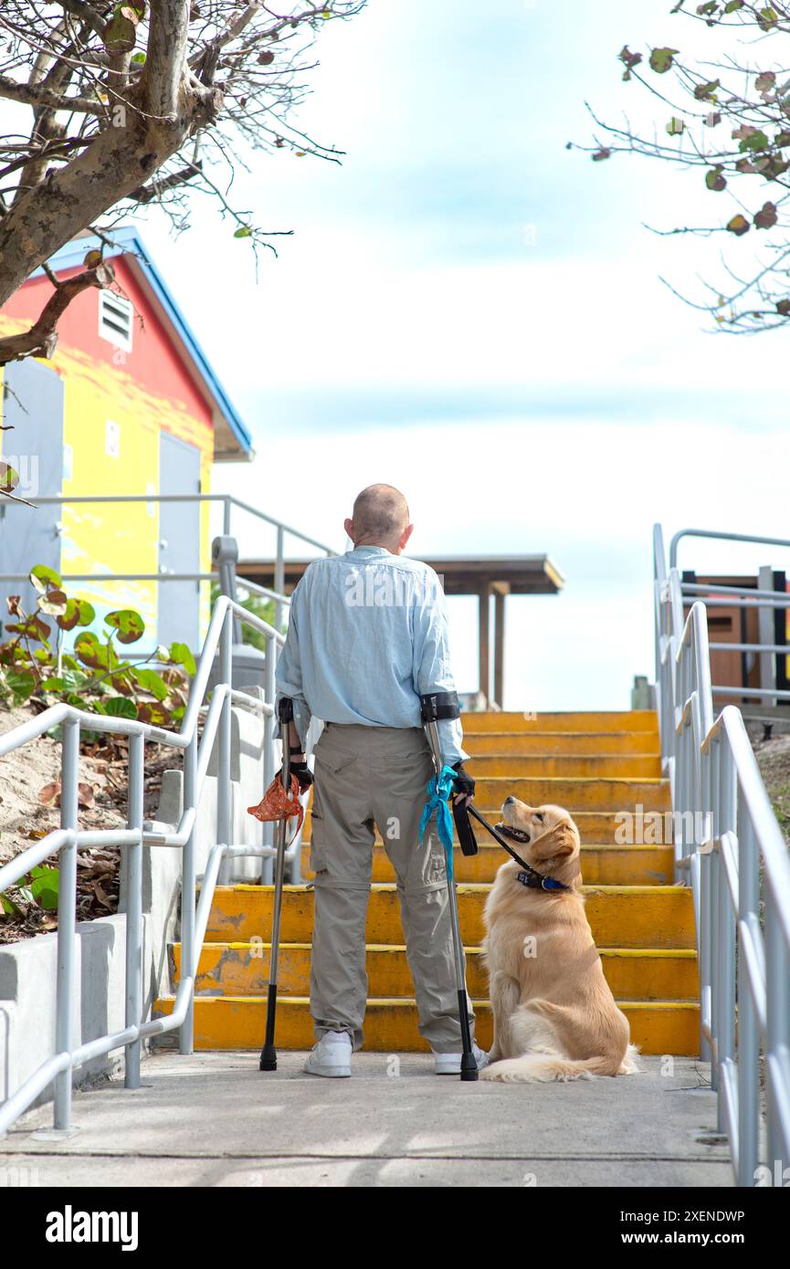 Paraplegic man with forearm crutches stands at the bottom of steps with ...