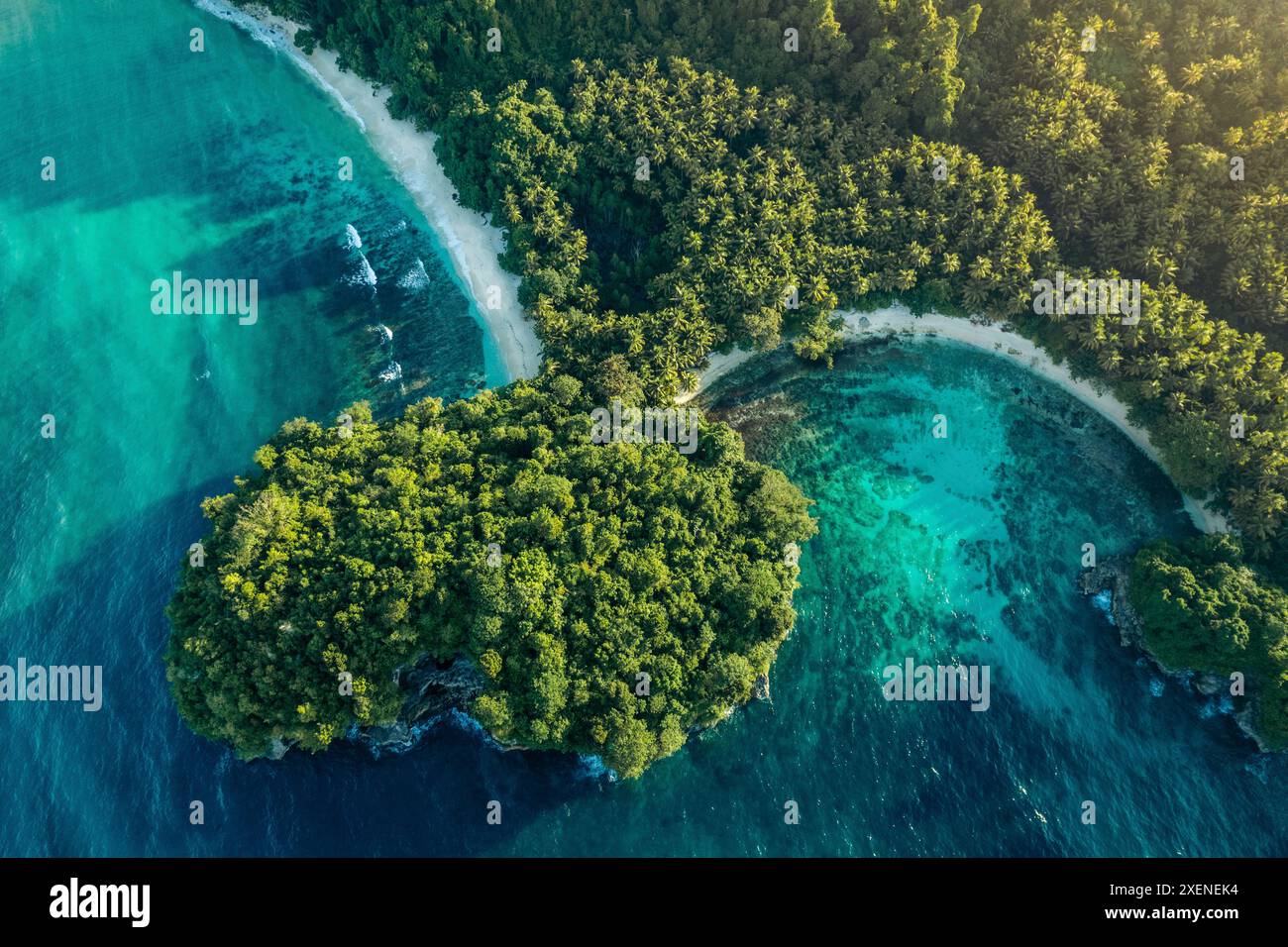 White sand beach and lush trees in warm sunlight at Pantai Bakum along ...