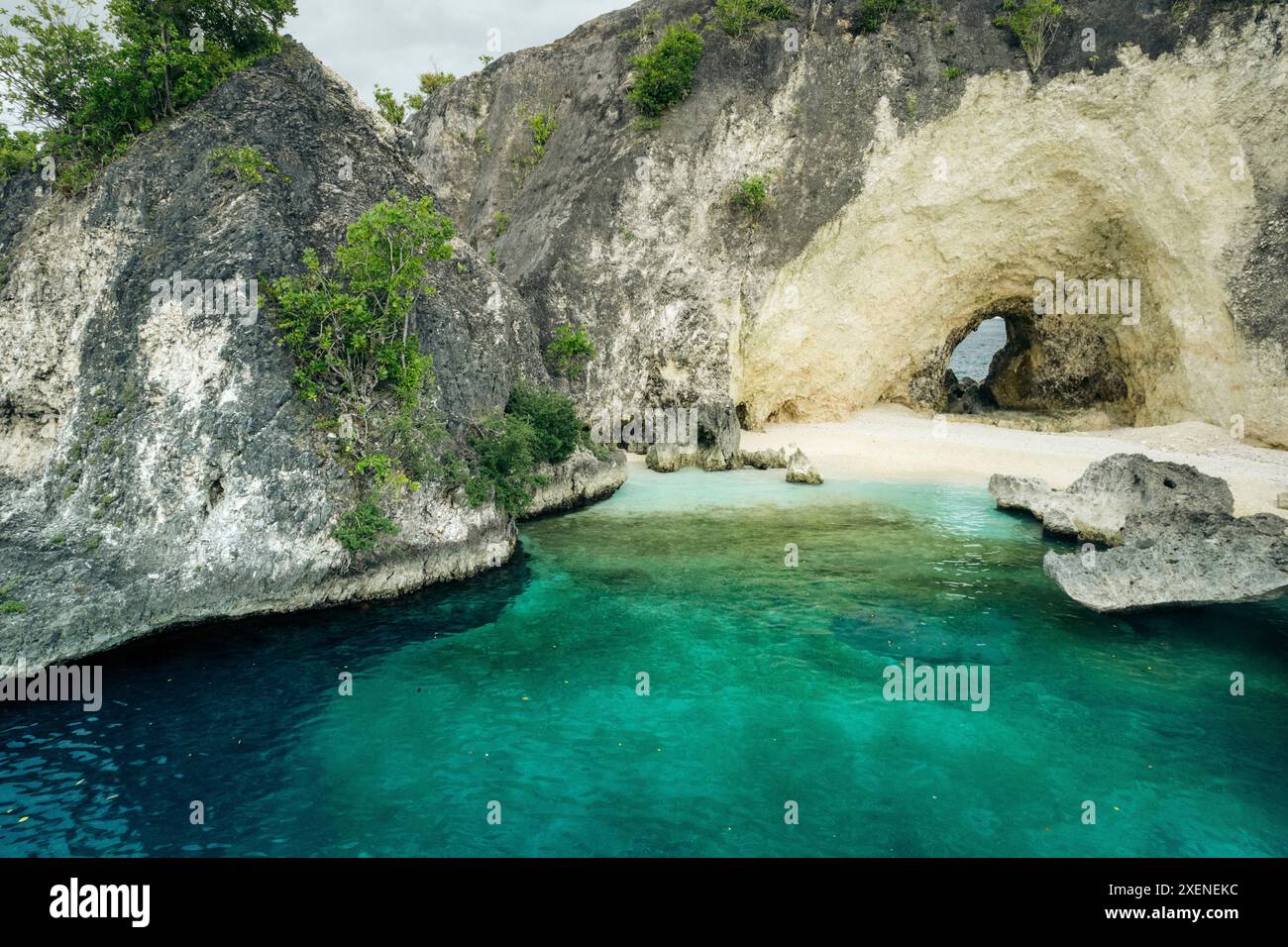 White sand beach with natural arch along a rugged coastline in the ...