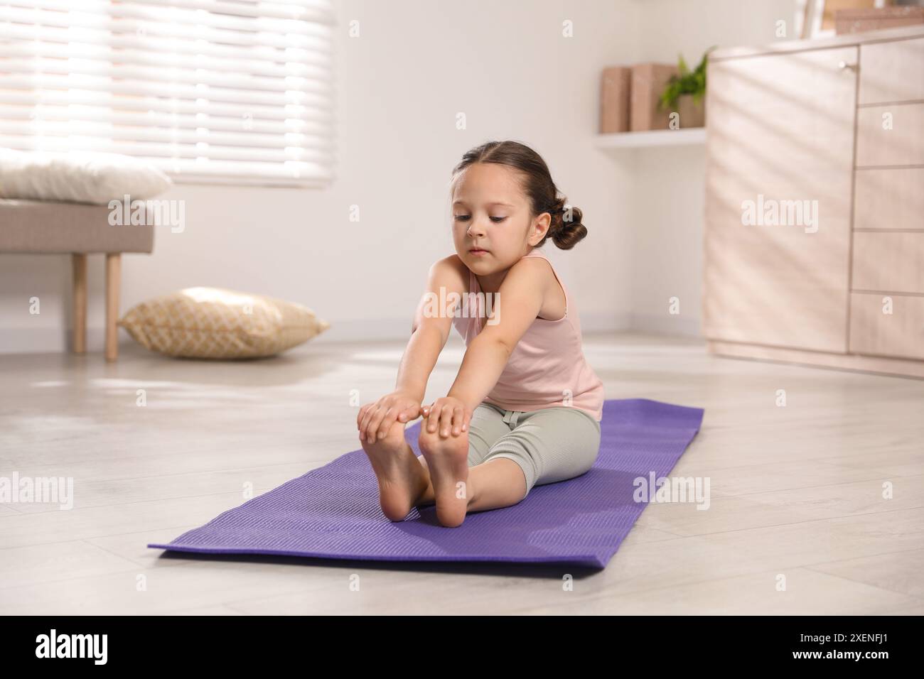 Cute little girl stretching herself on mat at home Stock Photo - Alamy