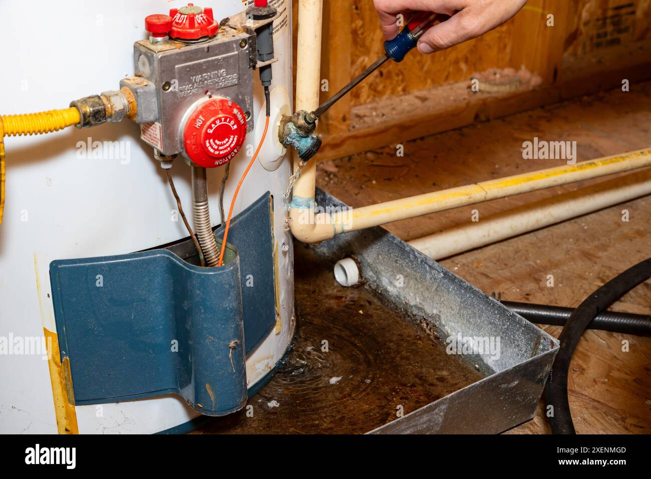 Screwdriver closing drain valve on water heater Stock Photo - Alamy