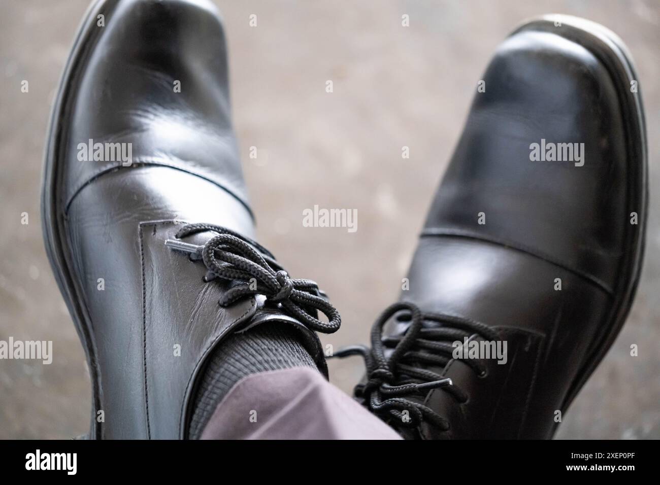 Close-up of a person wearing black leather dress shoes with laces ...