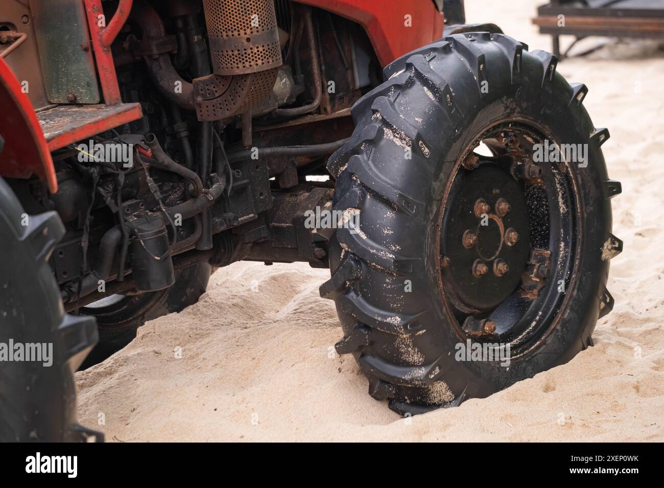 Close-up of a tractor wheel stuck in sand, showing the tire tread and ...