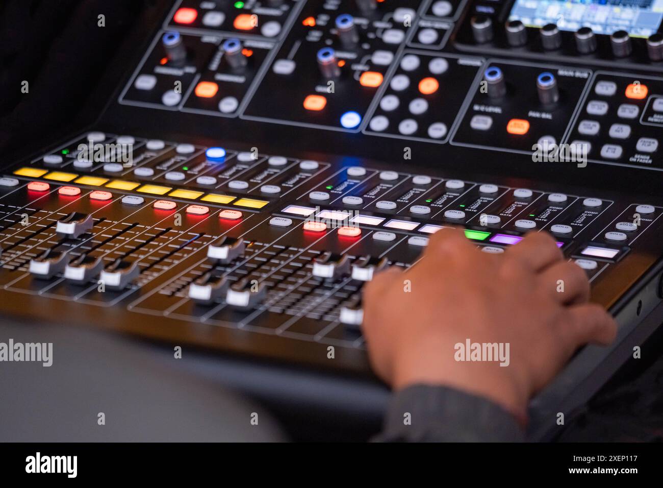 Close-up of a person operating a professional audio mixing console with ...