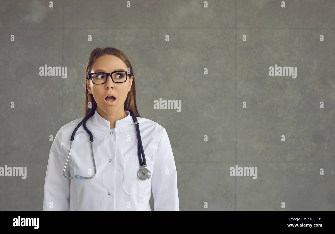 Shocked young female doctor with open mouth looking aside studio ...