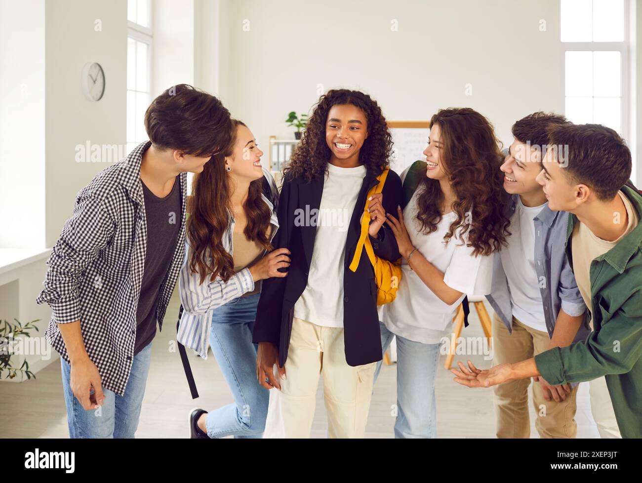 Group of a happy laughing school students standing together in classroom and hugging Stock Photo ...