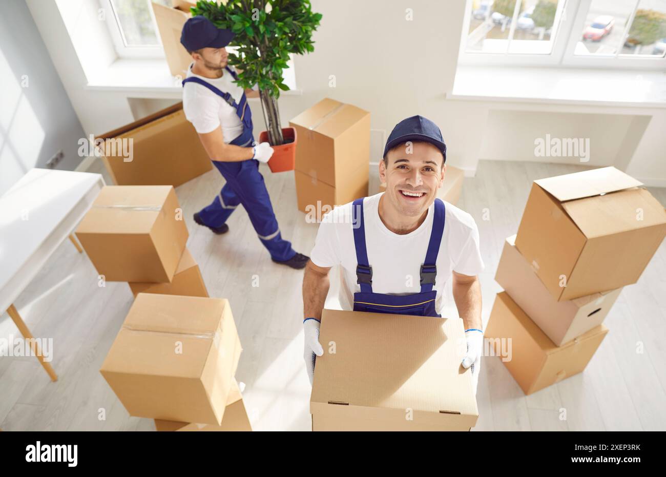 Happy employee of moving service standing in new house holding ...