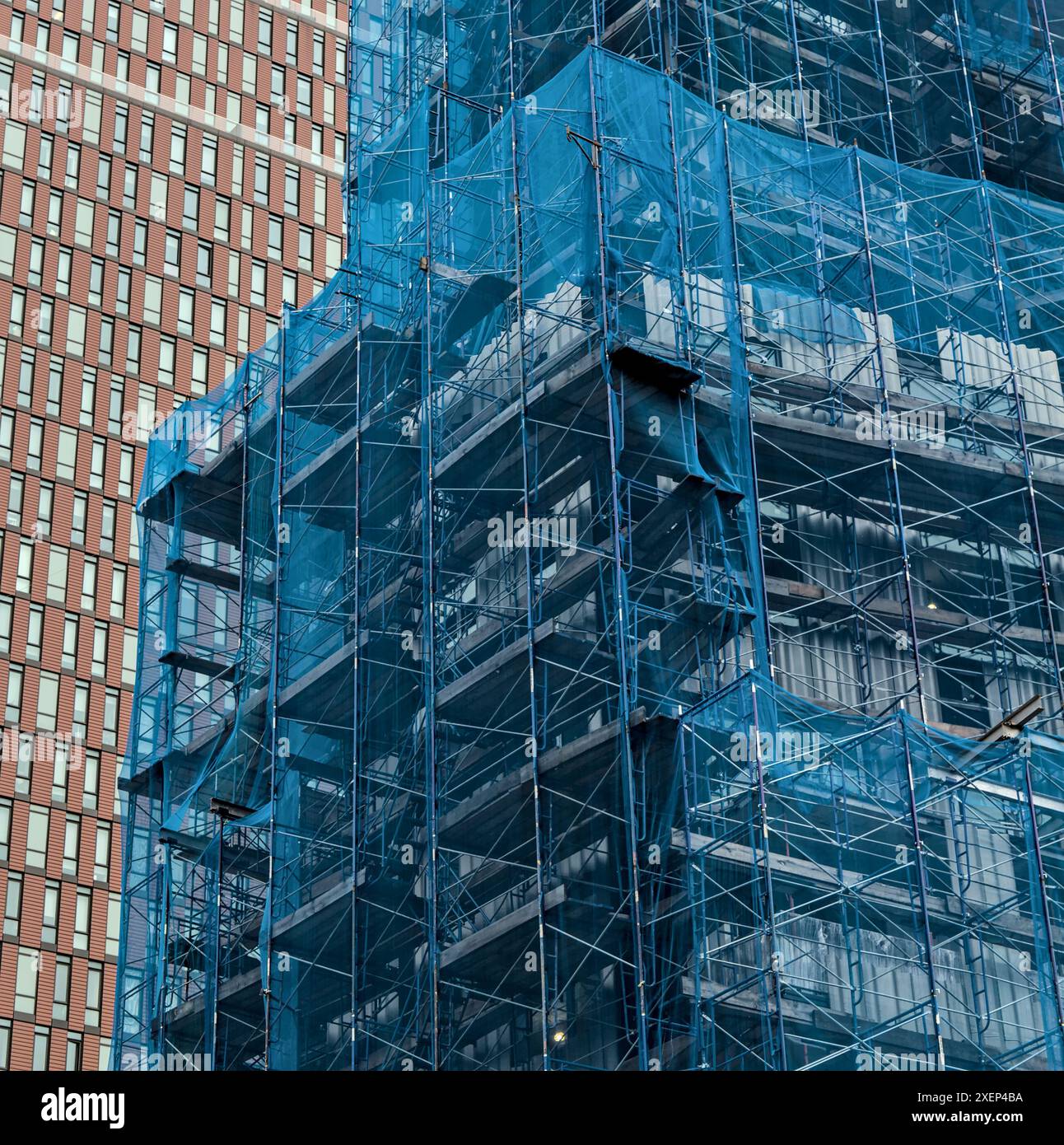 building under construction covered in blue mesh tarp protective wrap ...