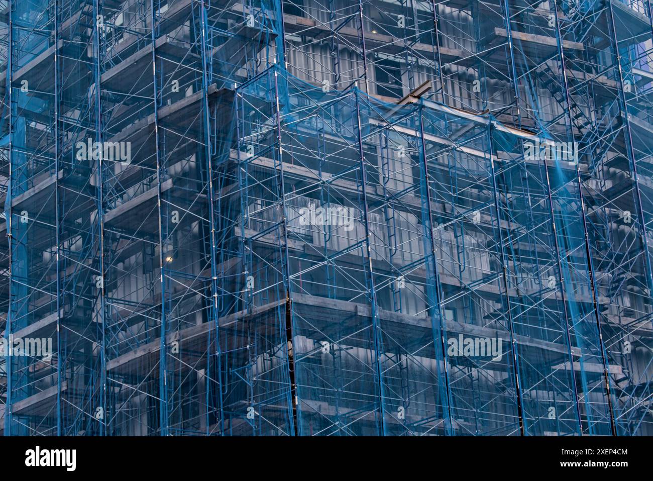 building under construction covered in blue mesh tarp protective wrap ...