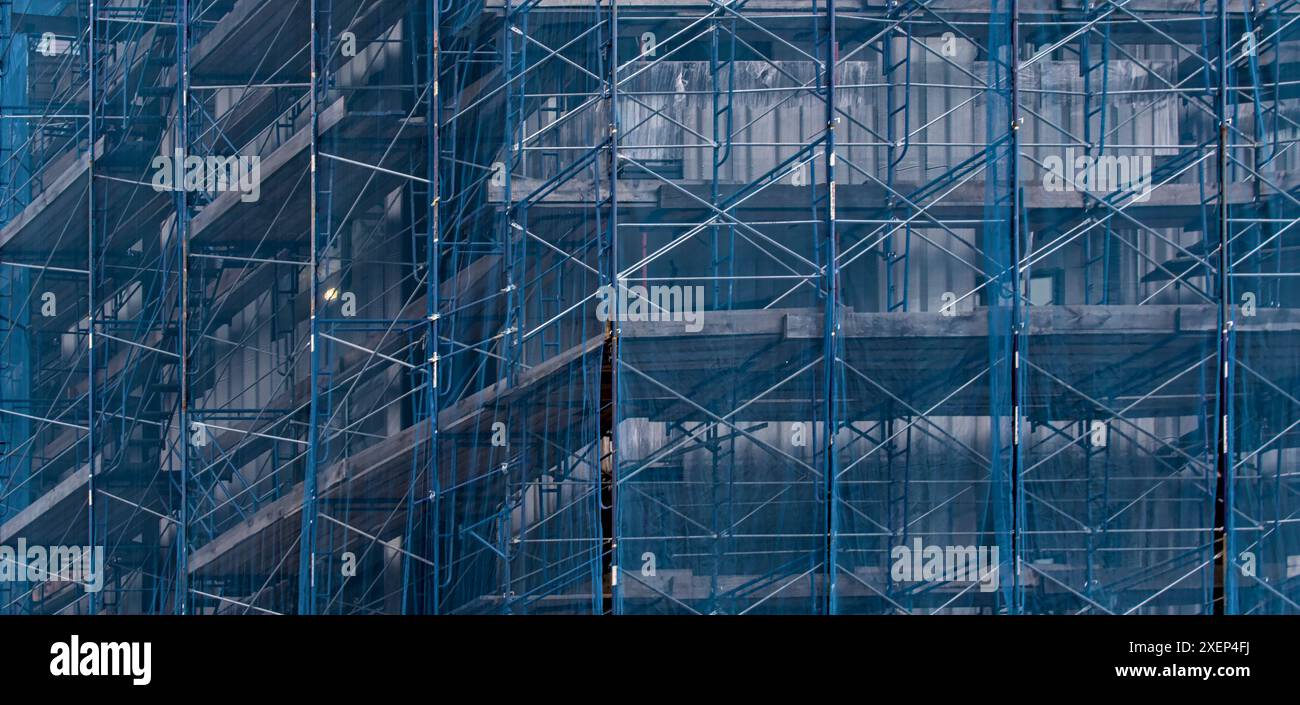 building under construction covered in blue mesh tarp protective wrap ...