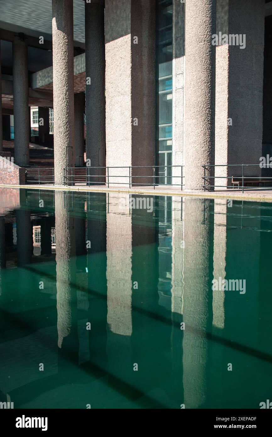 Brutal concrete structure of the Barbican reflected in the green water ...