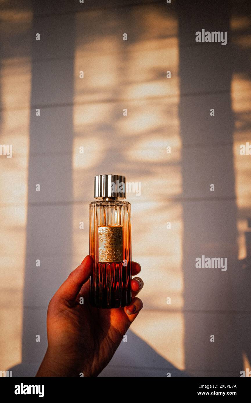 woman's hand holding perfume in light Stock Photo - Alamy