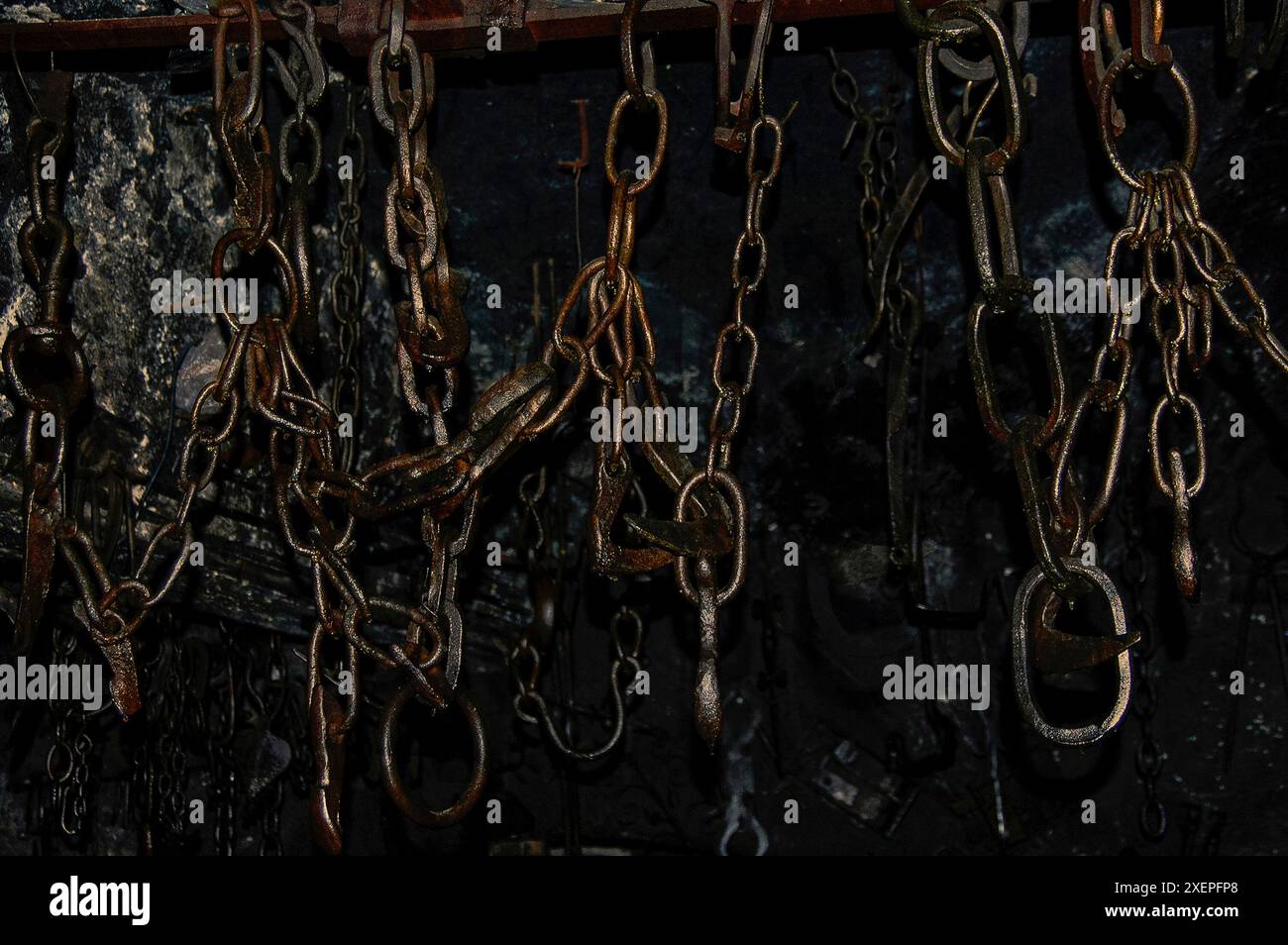Gleaming iron chains hang from a beam inside the Riepler Schmiede, a ...