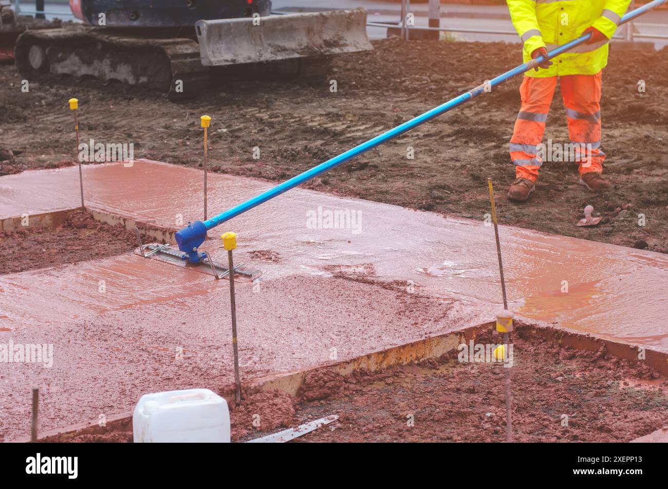 Builders pouring and leveling wet ready-mix concrete into formwork ...