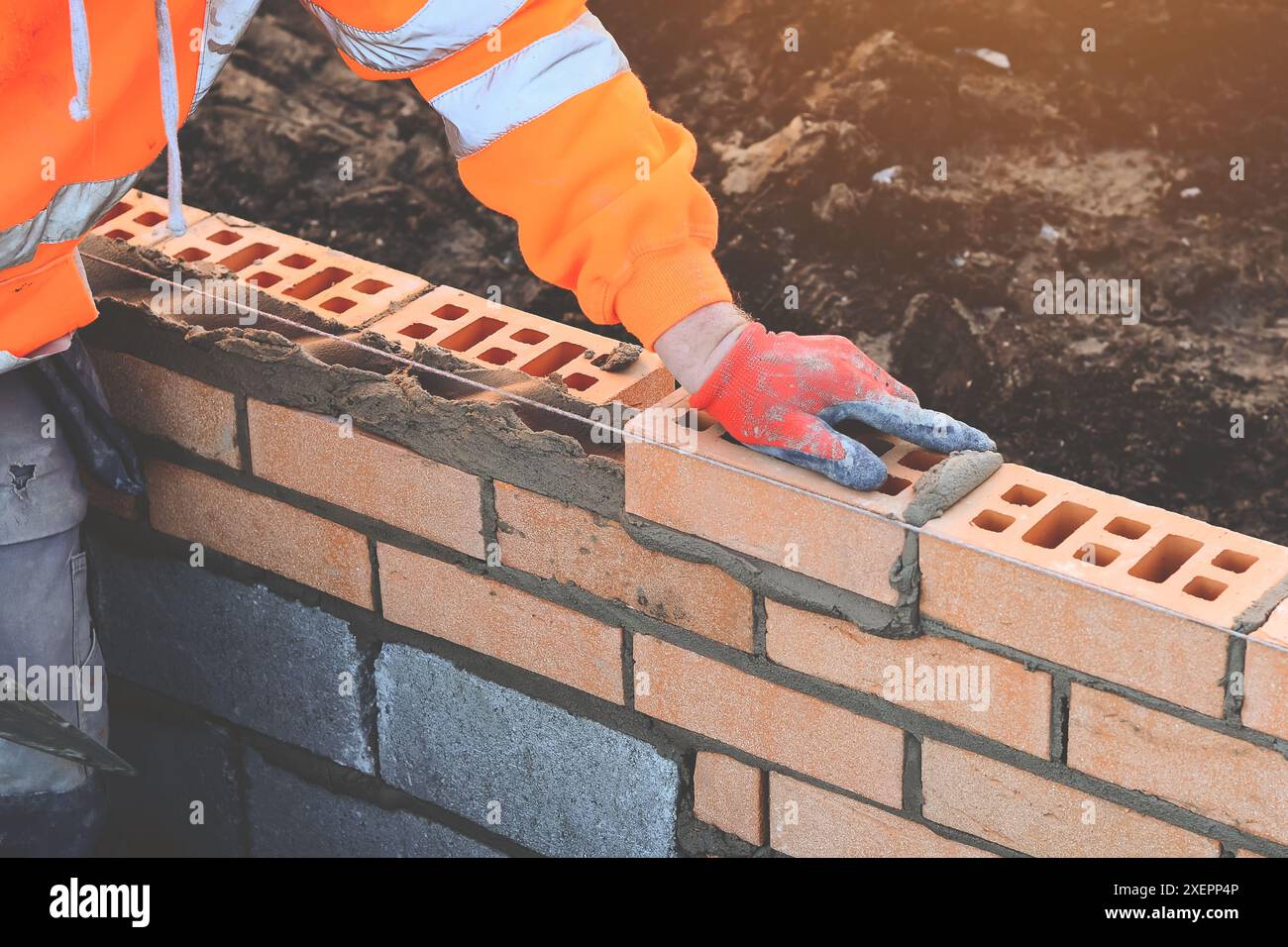 Industrial bricklayer laying bricks on cement mix on construction site ...