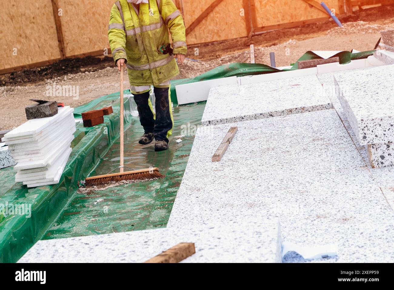 Builder placing polystyrene insulation boards on waterproofing membrane ...