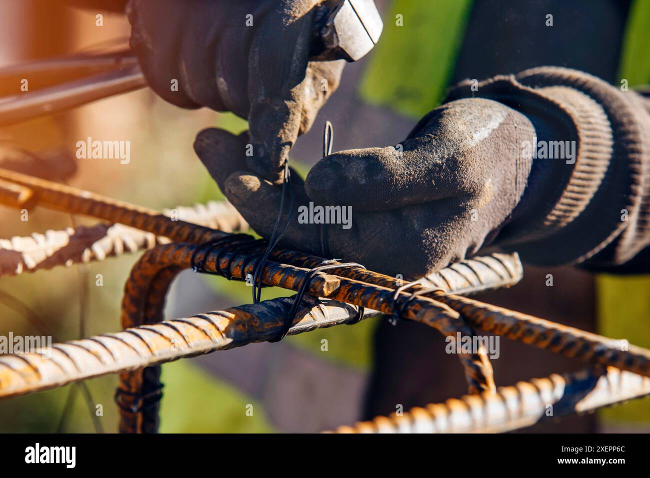 A worker uses steel tying wire to fasten steel rods to reinforcement ...