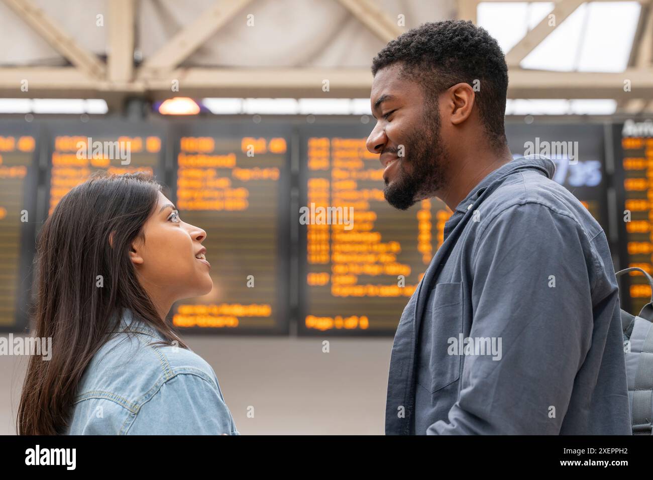 Group of multiracial friends checking time on departure board at a ...
