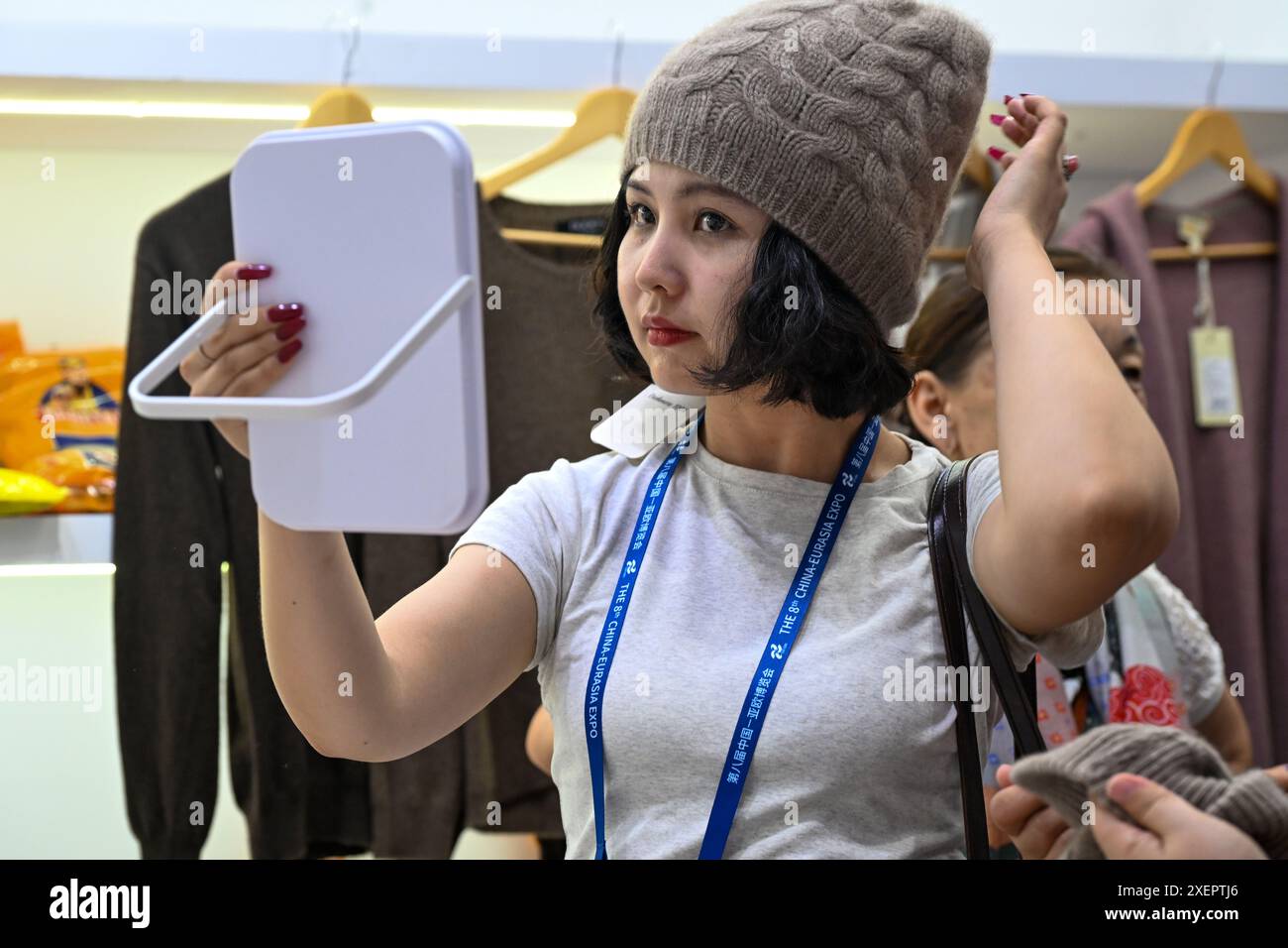 (240629) -- URUMQI, June 29, 2024 (Xinhua) -- A visitor tries on a cap ...