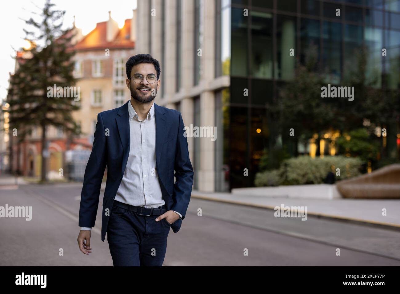 Smiling businessman walking confidently through city street in modern ...