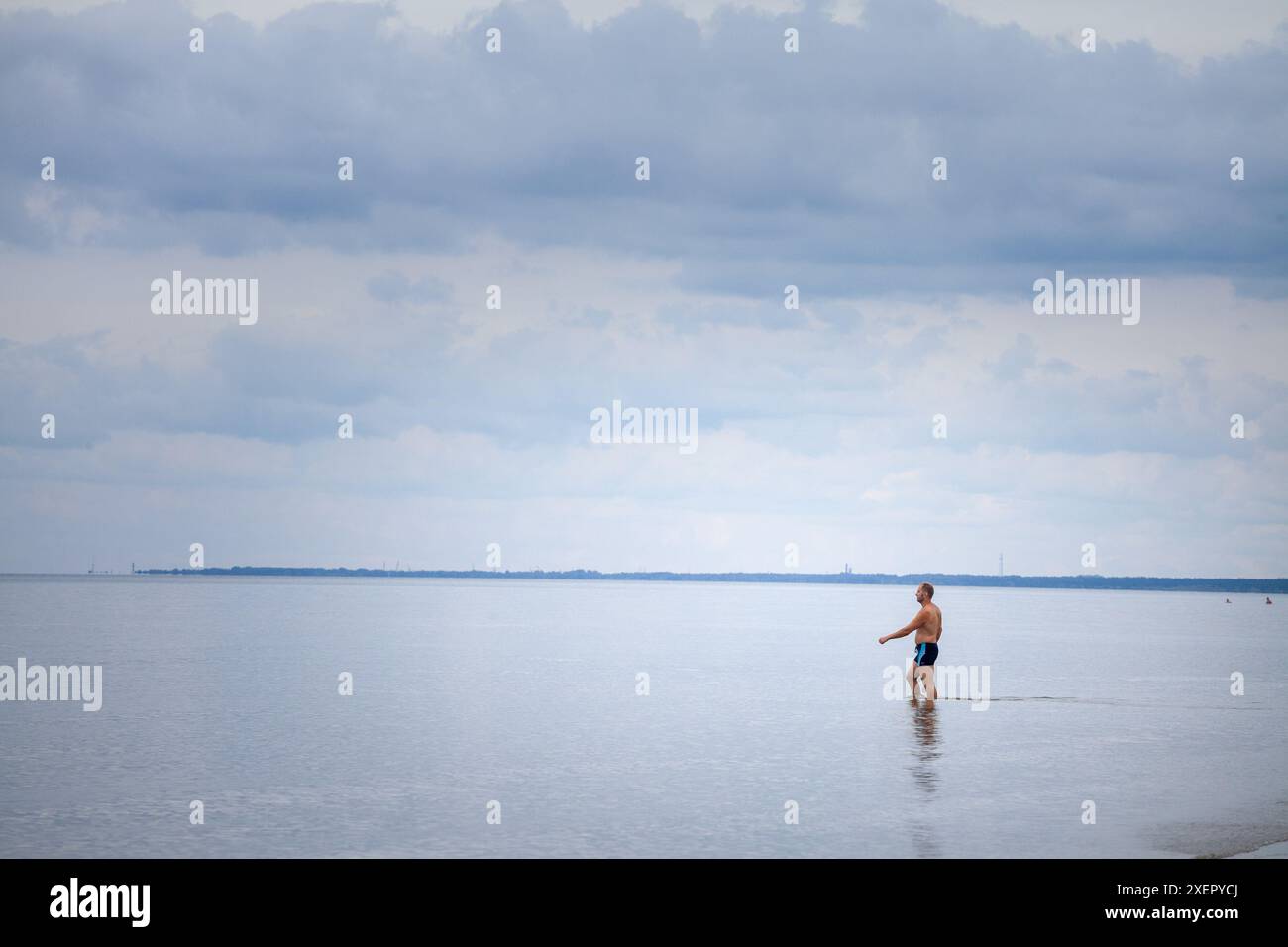 A man enters the tranquil waters of the Baltic Sea at Jurmala Beach in ...