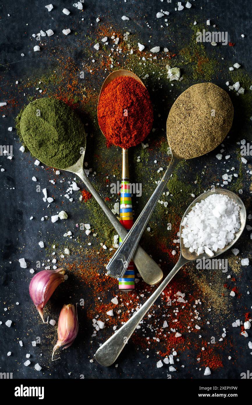 Spoons with spices on black background sprinkled with different kind of ...