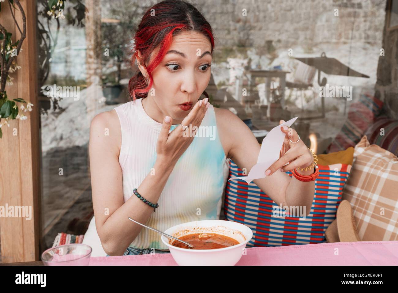 Shocked woman at a restaurant confronted with an unexpectedly expensive ...