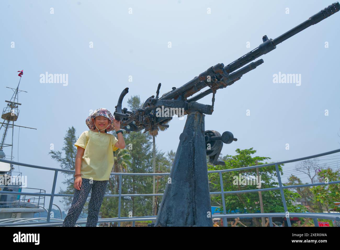 Portrait of Asian little tourist with a machine gun of old battleship ...