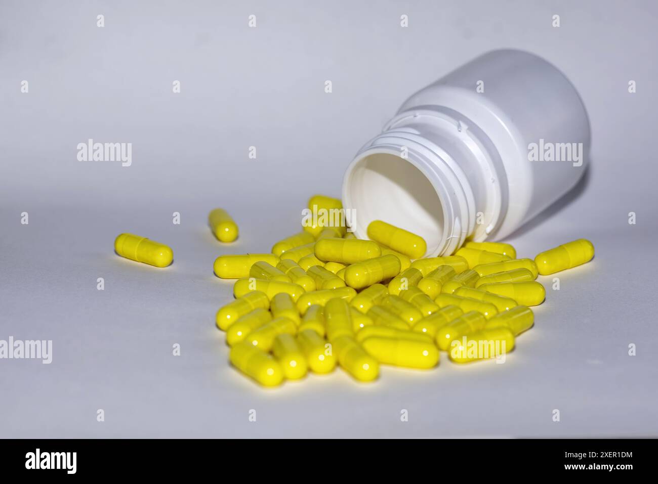 Yellow capsules spilled from a medicine bottle, representing health ...