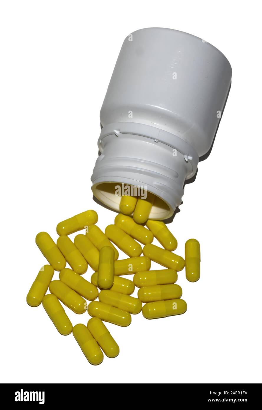 Yellow capsules spilled from a medicine bottle isolated on white or ...