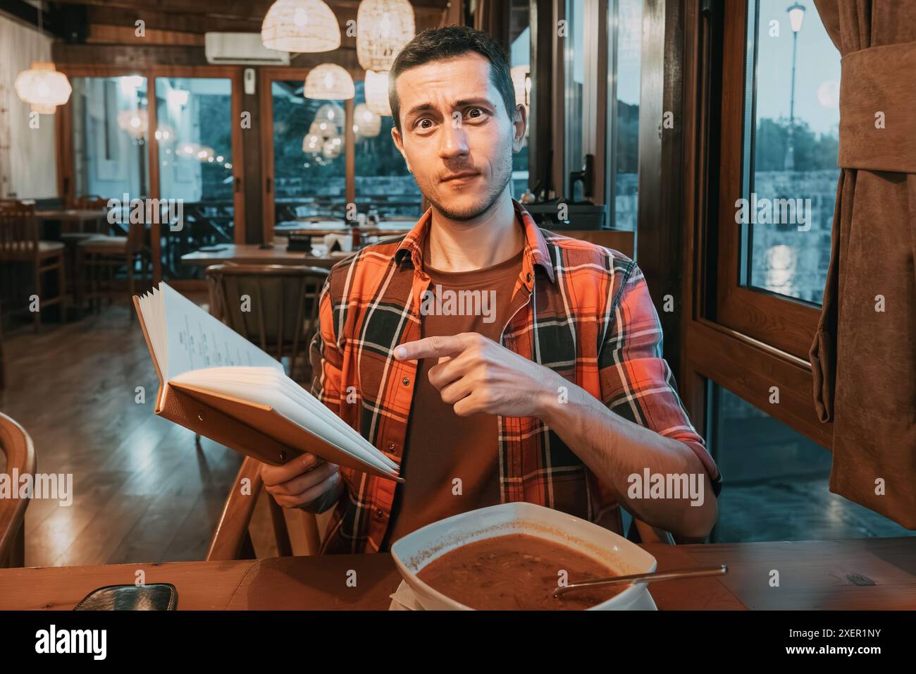 A person sitting at a cafe table, pondering food choices while reading ...