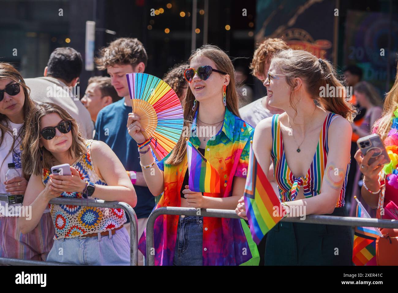 London, UK 29 June 2024. Revellers wave rainbow coloured fans and flags ...