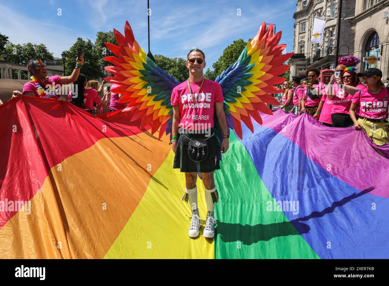 London, UK. 29th June, 2024. walks underneath. The giant Pride flag is ...