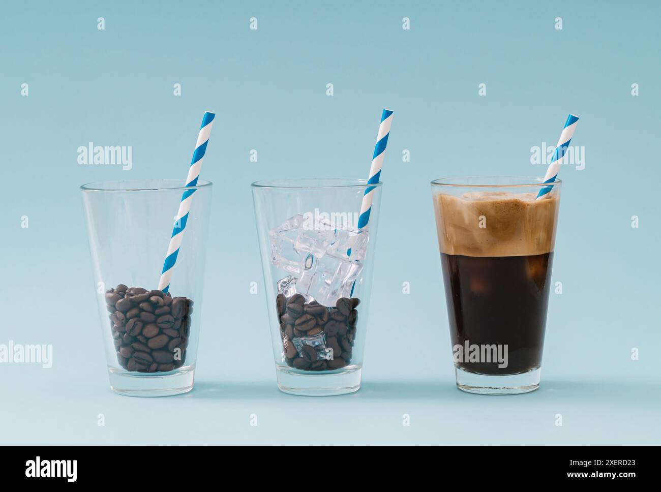 Creative layout made with three glass cups, roasted coffee beans, ice cubes, iced coffee and ...