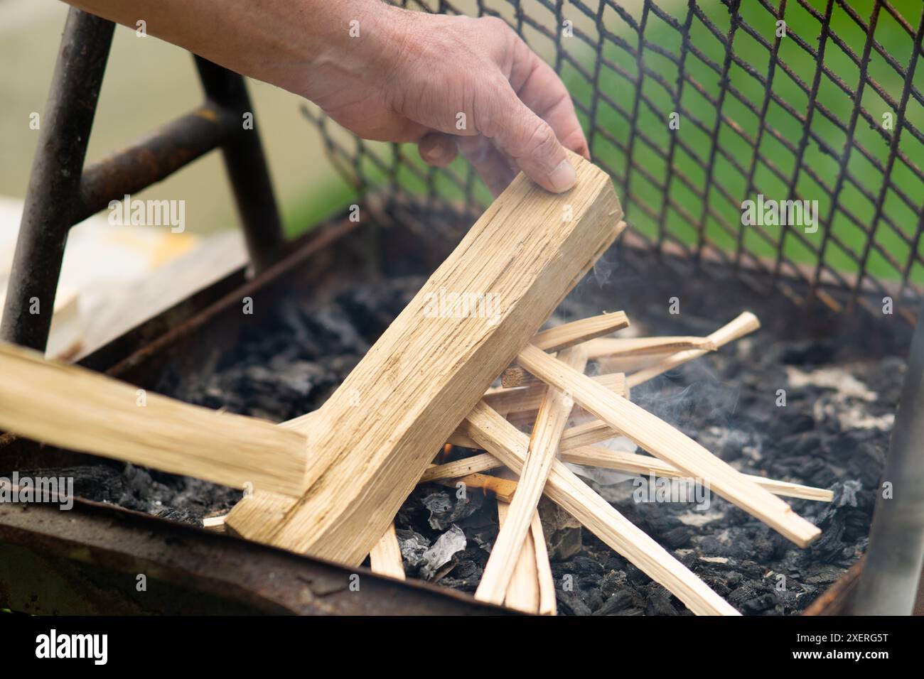 A man light a fire on an outdoor grill using wood sticks, preparing ...