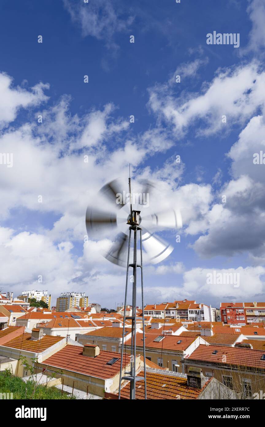 Windmill stands tall above the rooftops of lisbon, contrasting with the city's modern buildings ...