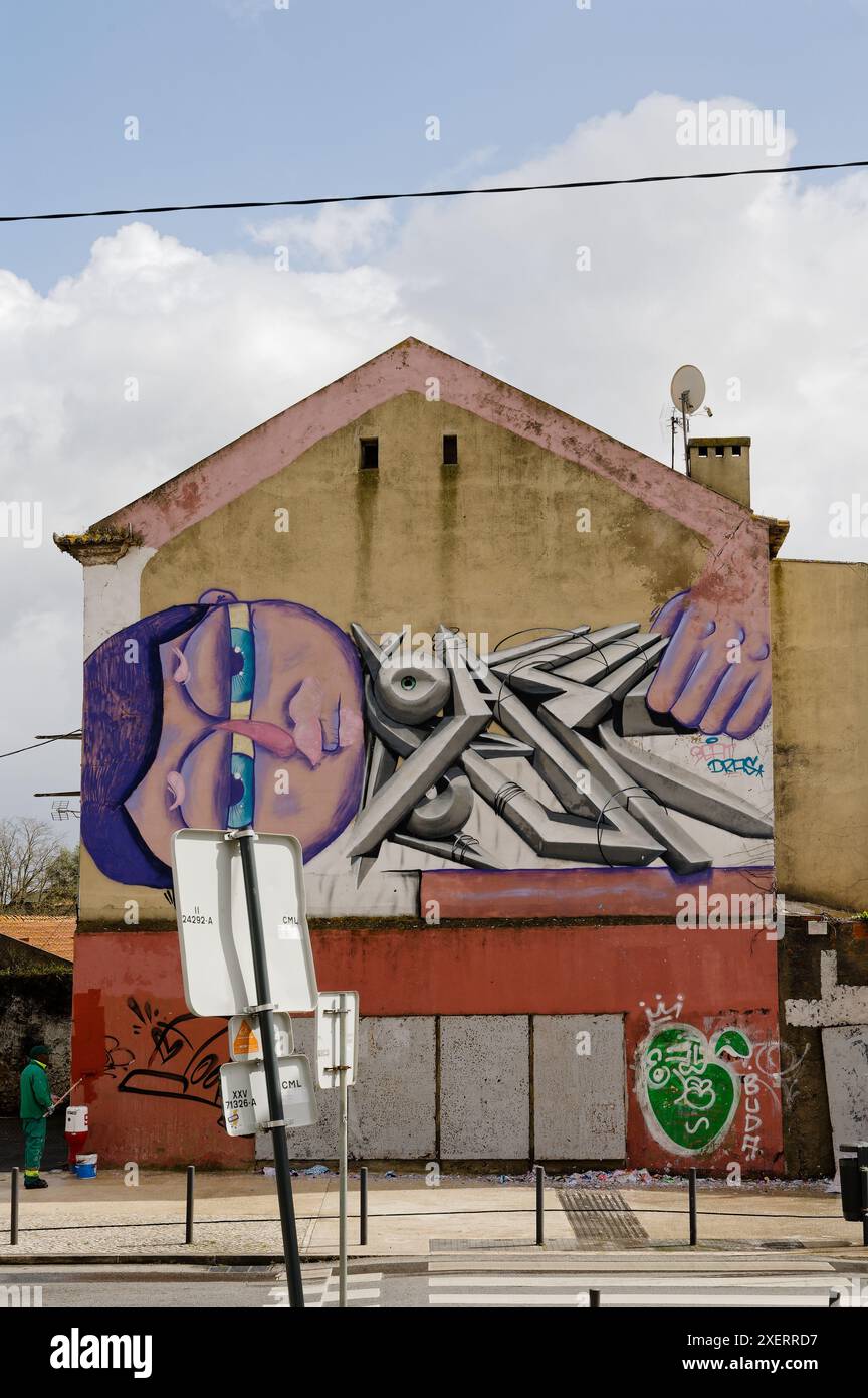 A painter in green starts to paint over graffiti on a weathered ...