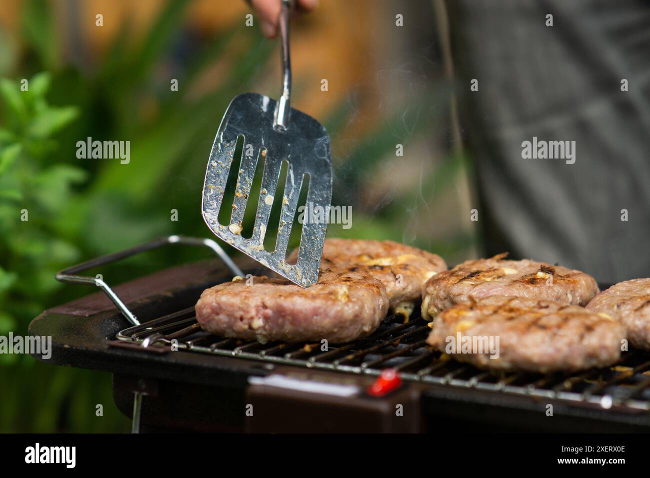 Man flipping burgers on grill hi-res stock photography and images - Alamy