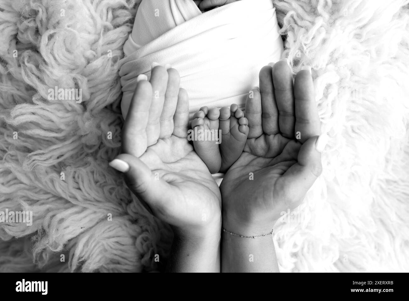 The palms of the father and mother are holding the foot of the newborn ...