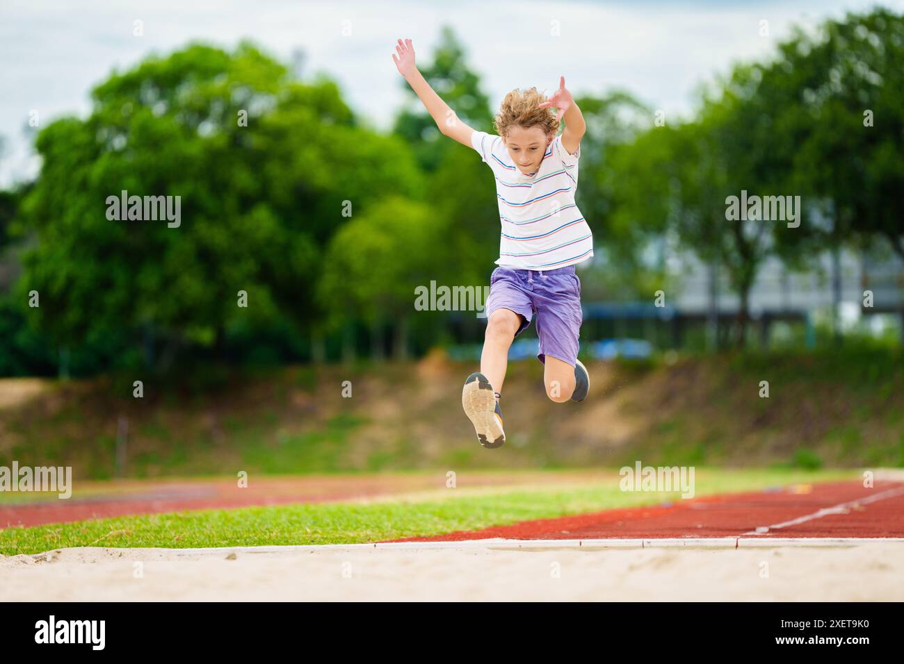 Kids long jump athletics training. Child jumping in sand pit on school ...