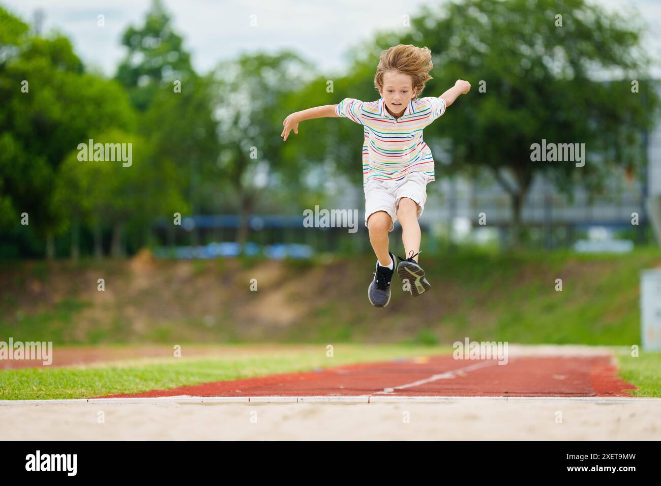 Kids long jump athletics training. Child jumping in sand pit on school ...