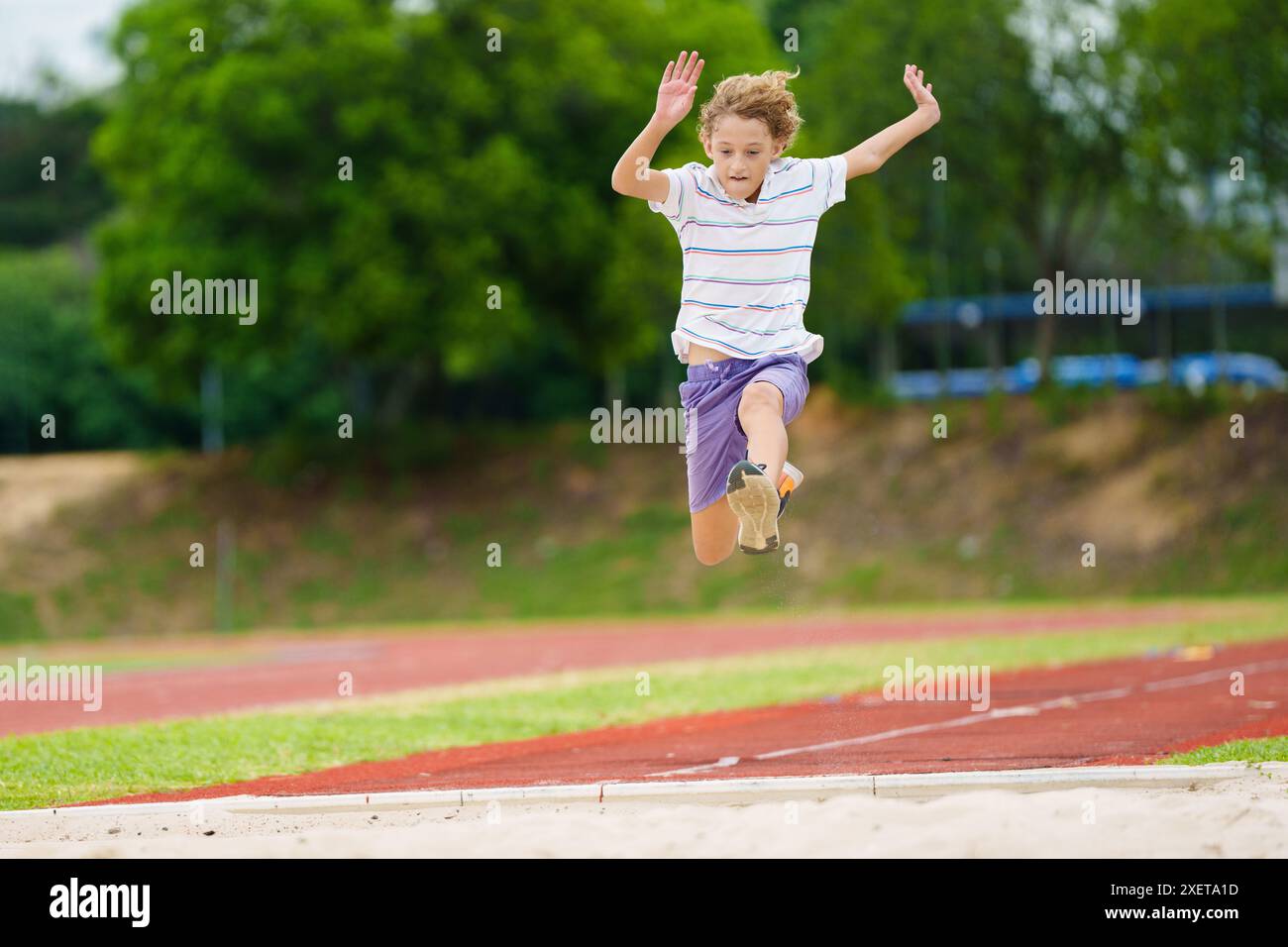 Kids long jump athletics training. Child jumping in sand pit on school ...