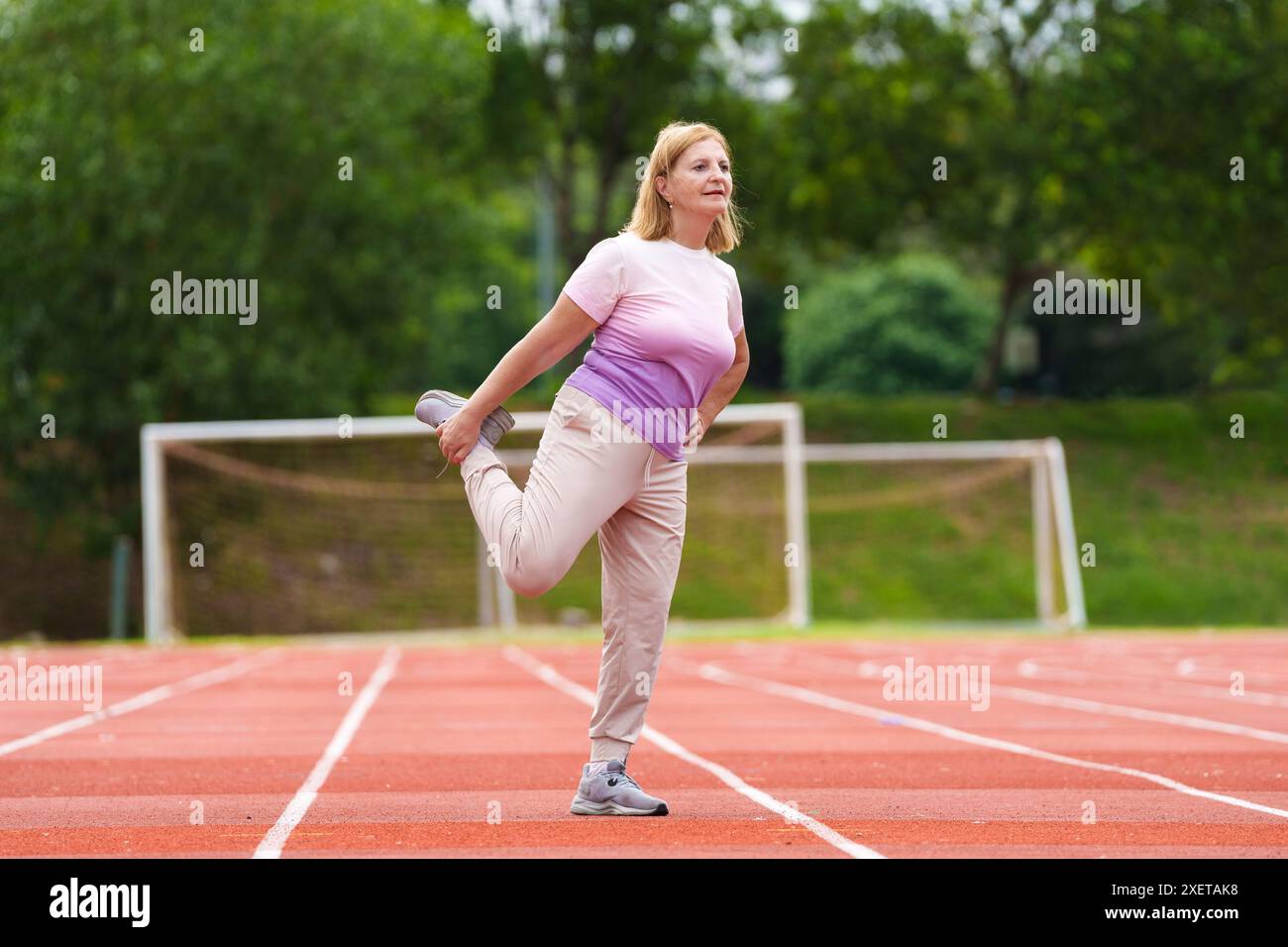 Elderly woman exercising. Fit senior lady running on sunny stadium in ...