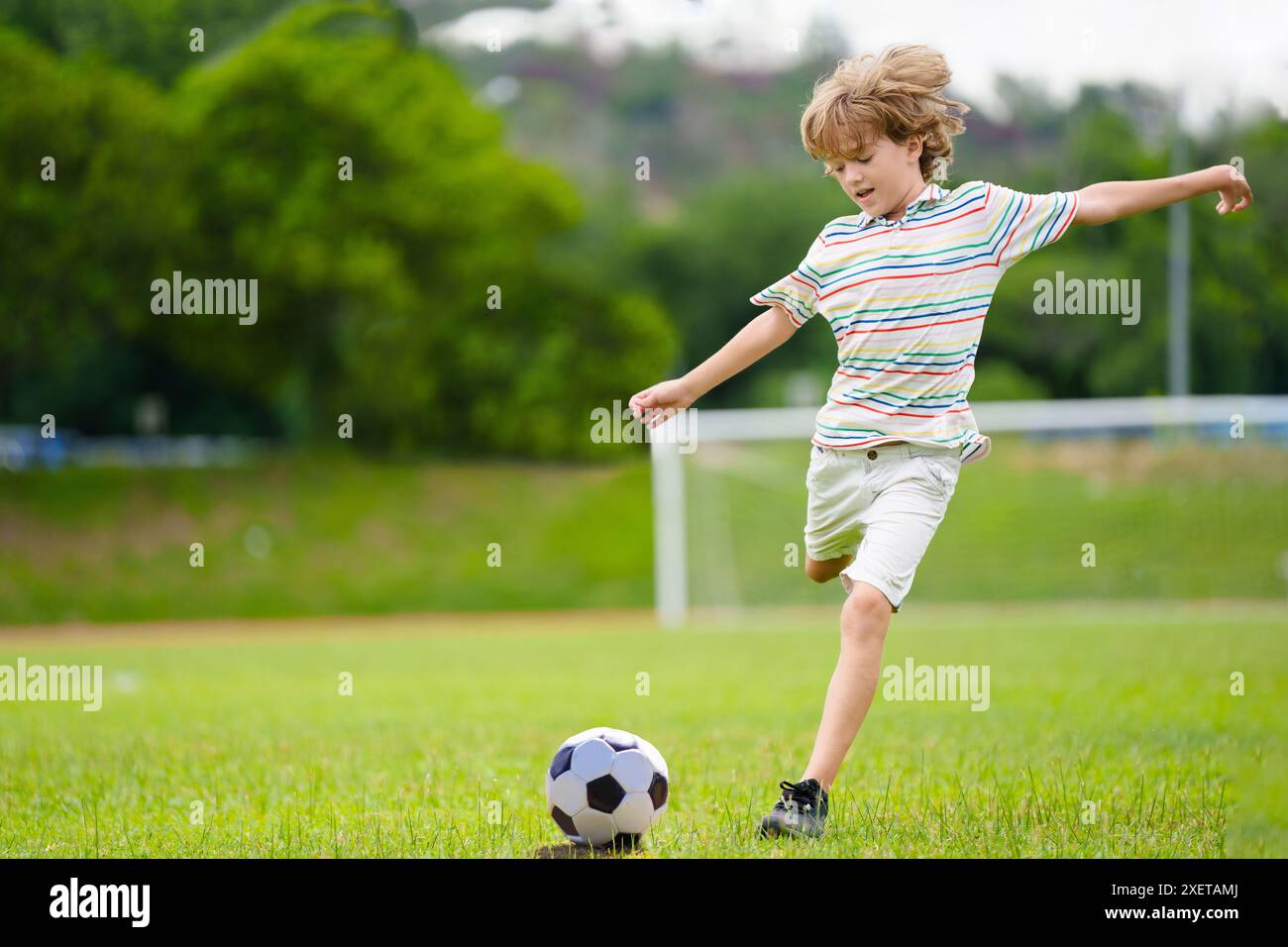 Child playing football. Kids play soccer on outdoor pitch. Little boy ...